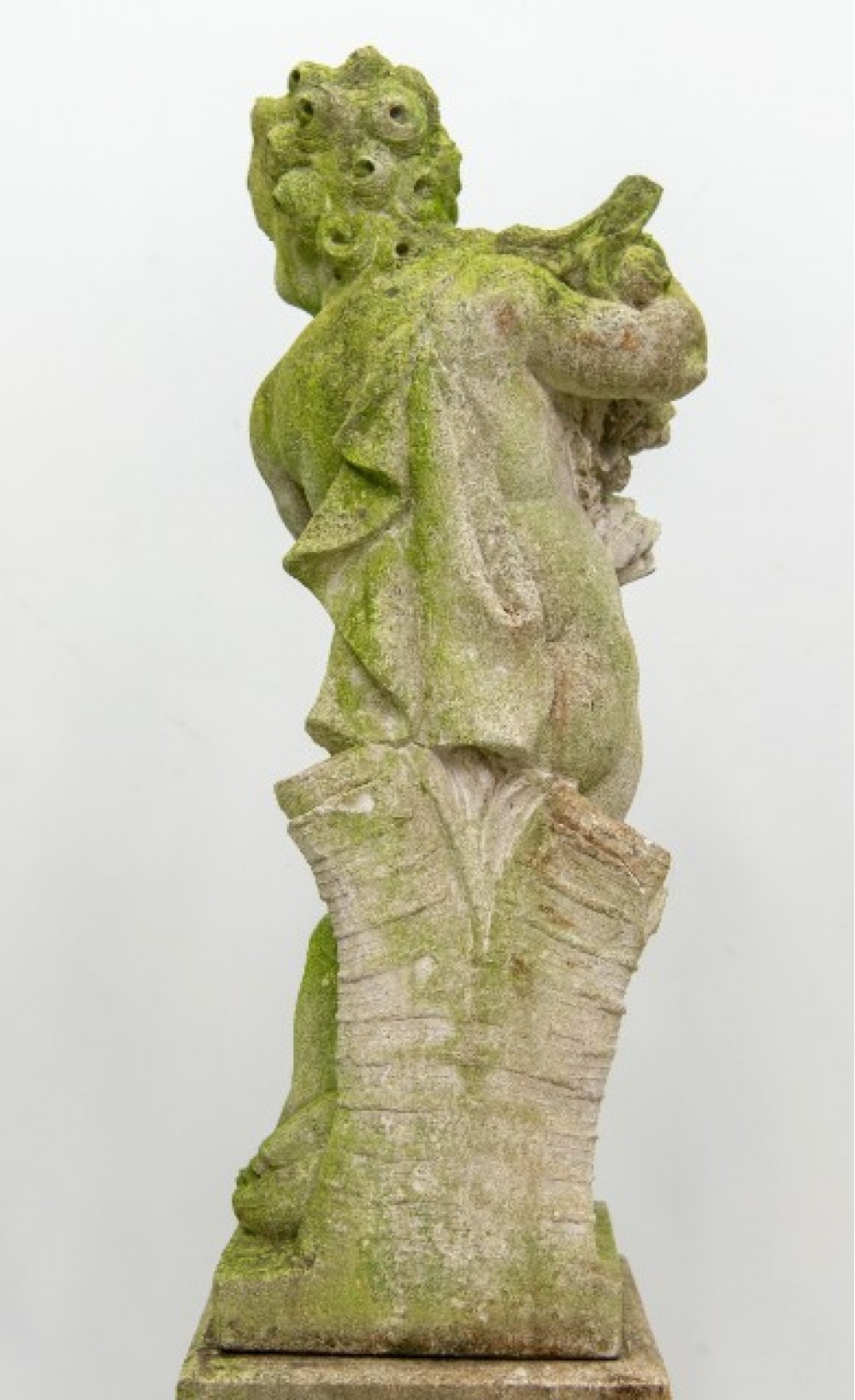 Concrete statue of cherub holding roses on base